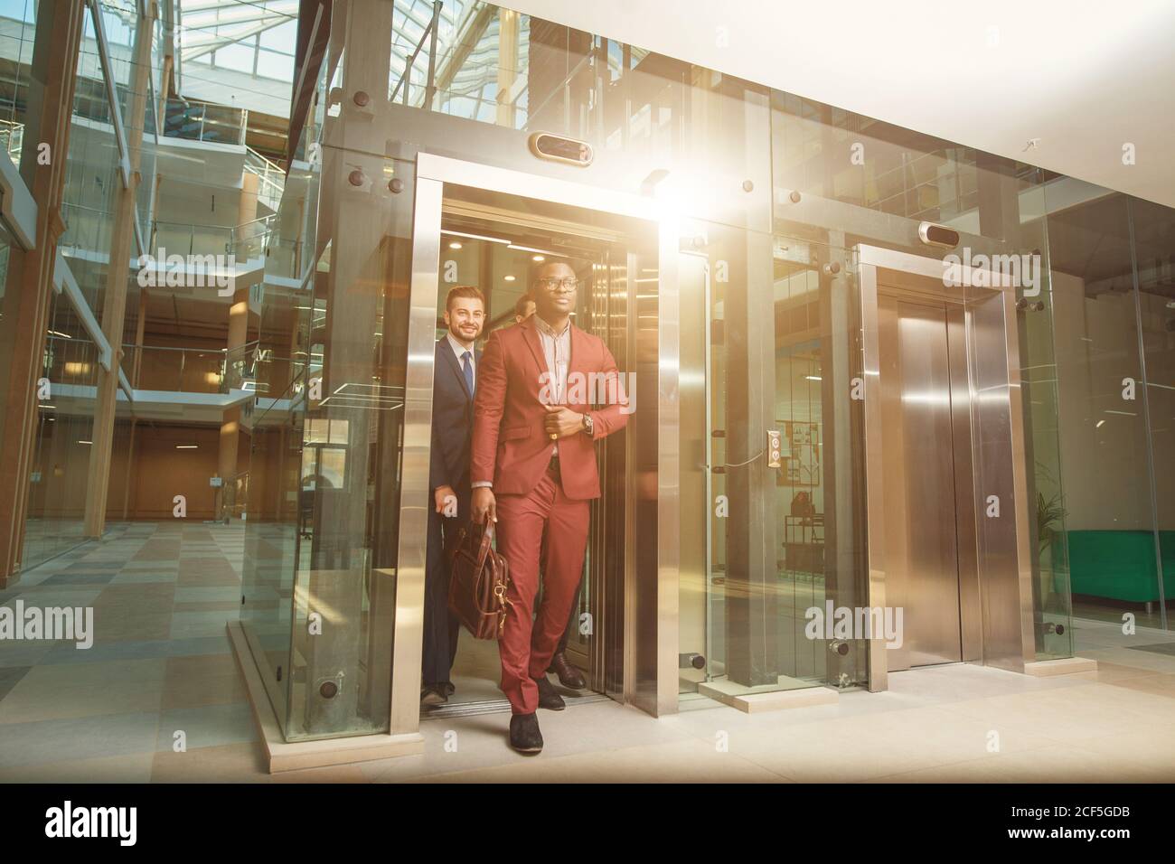 Business team group exit on elevator. Business people in a large glass ...