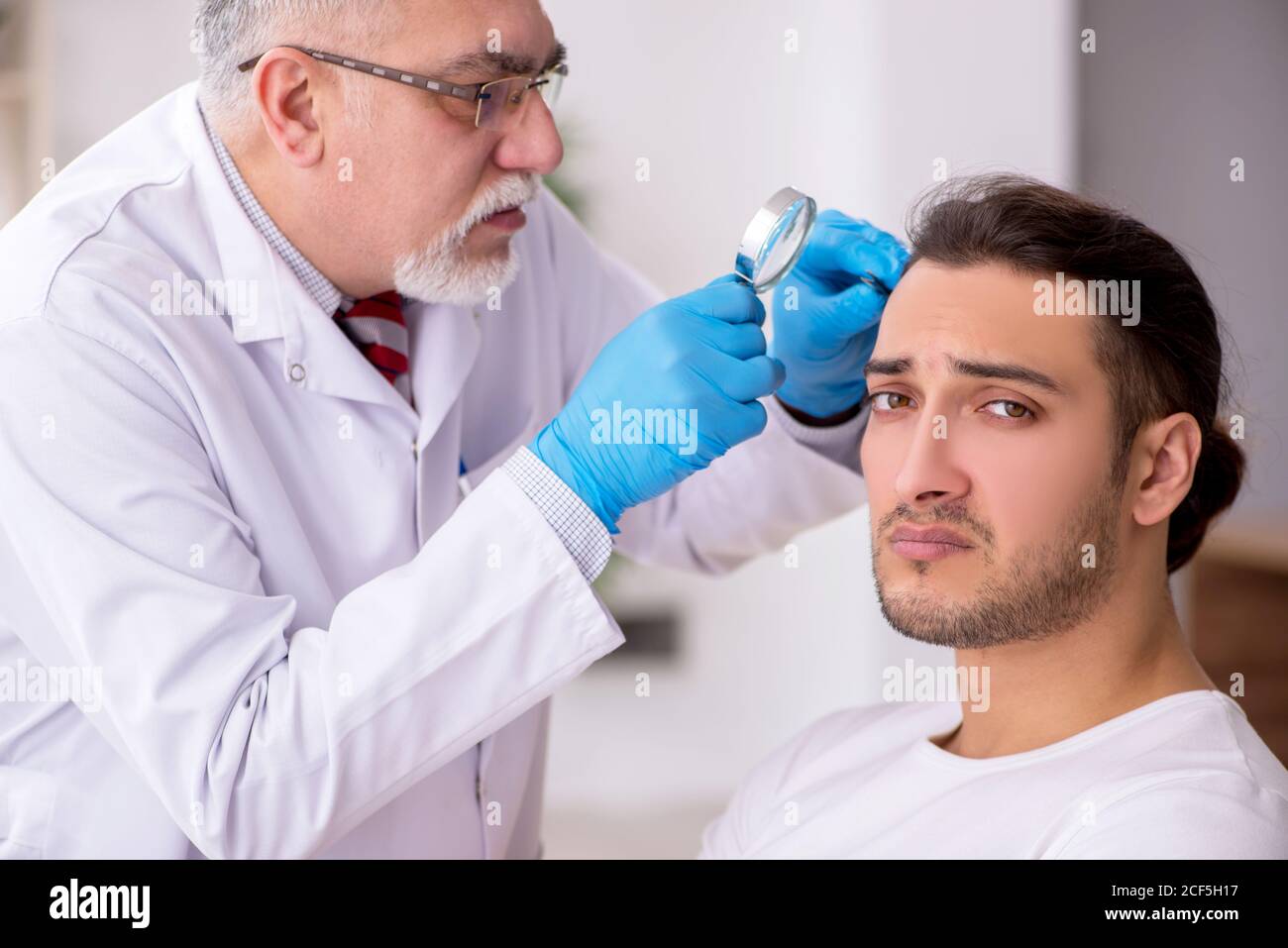 Young man visiting old doctor dermatologist Stock Photo - Alamy