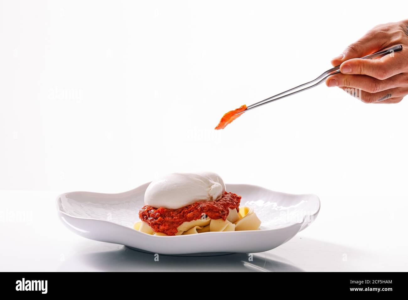 Crop hand with tweezers of unrecognizable chef preparing beautiful dish ...