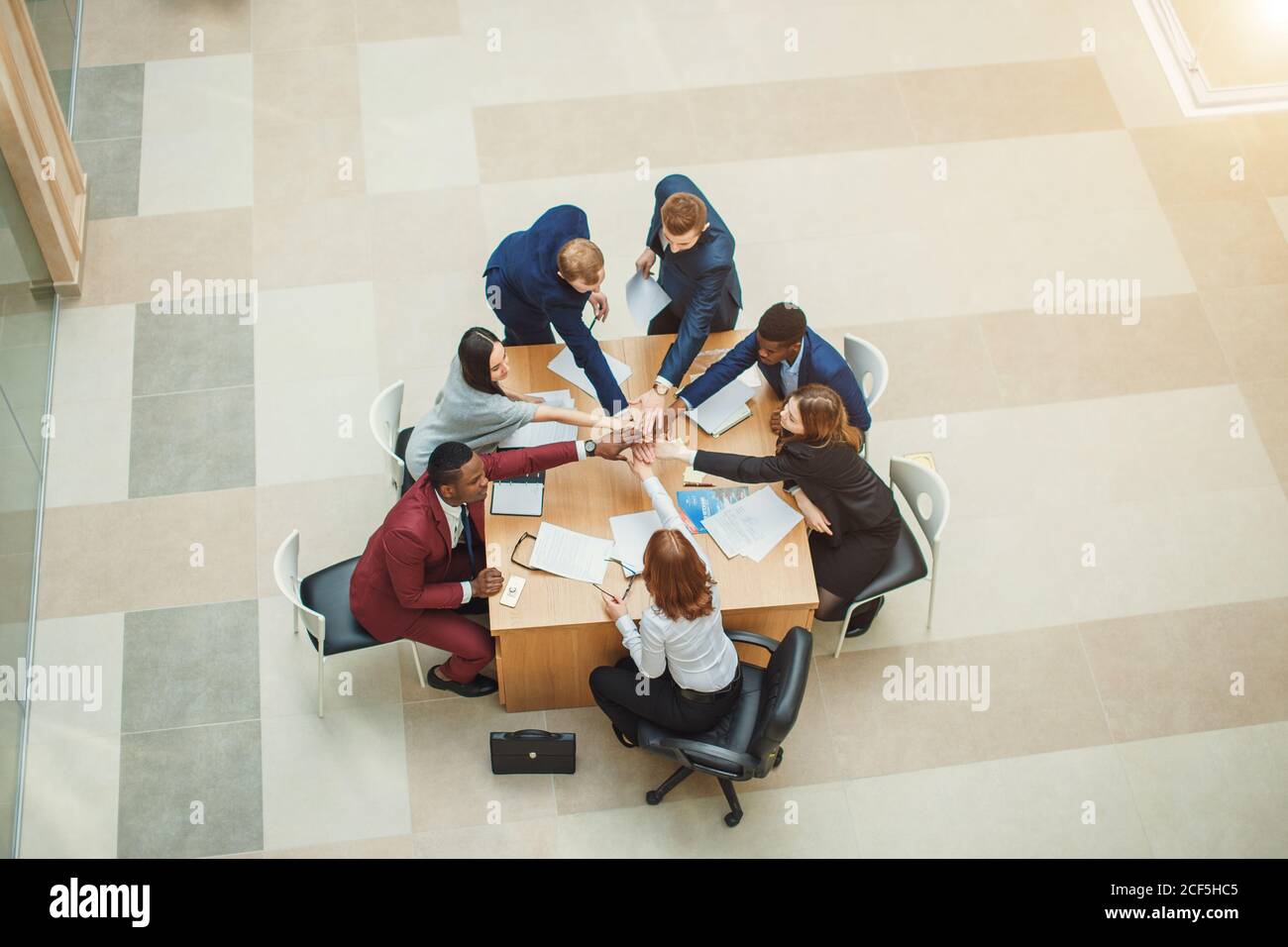 Team sitting behind desk, checking reports, talking. Top View Stock ...