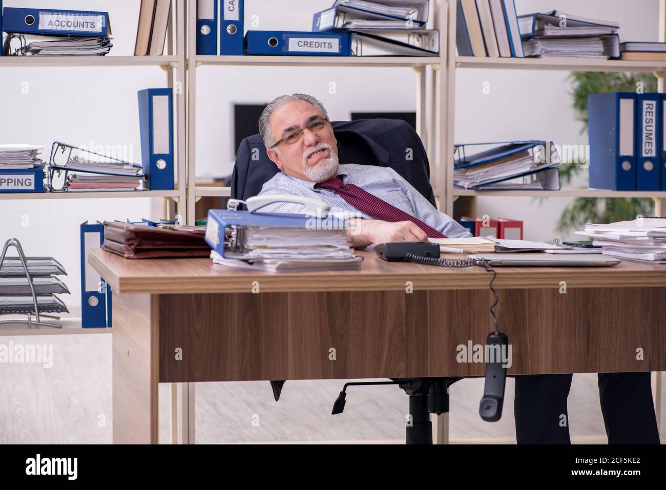 Old employee unhappy with excessive work Stock Photo - Alamy