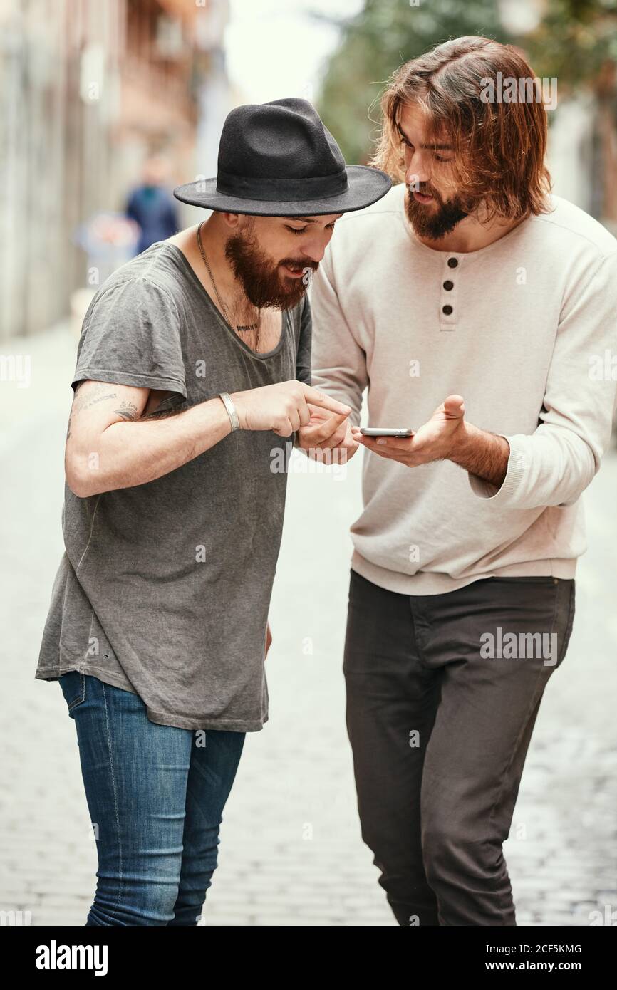 Handsome man in black hat standing with friend in street and pointing ...