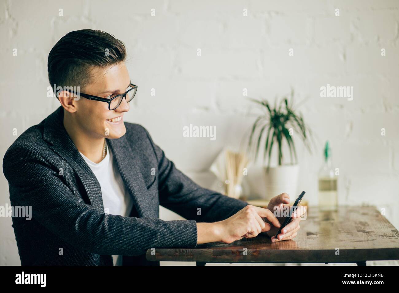 Texting to colleague. Confident young man in smart casual wear holding ...