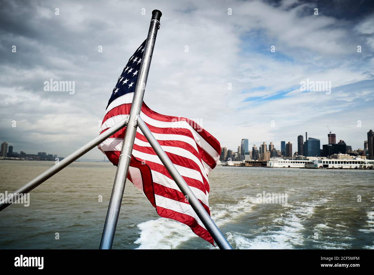 National flag of USA waving on pole of floating vessel against cloudy ...