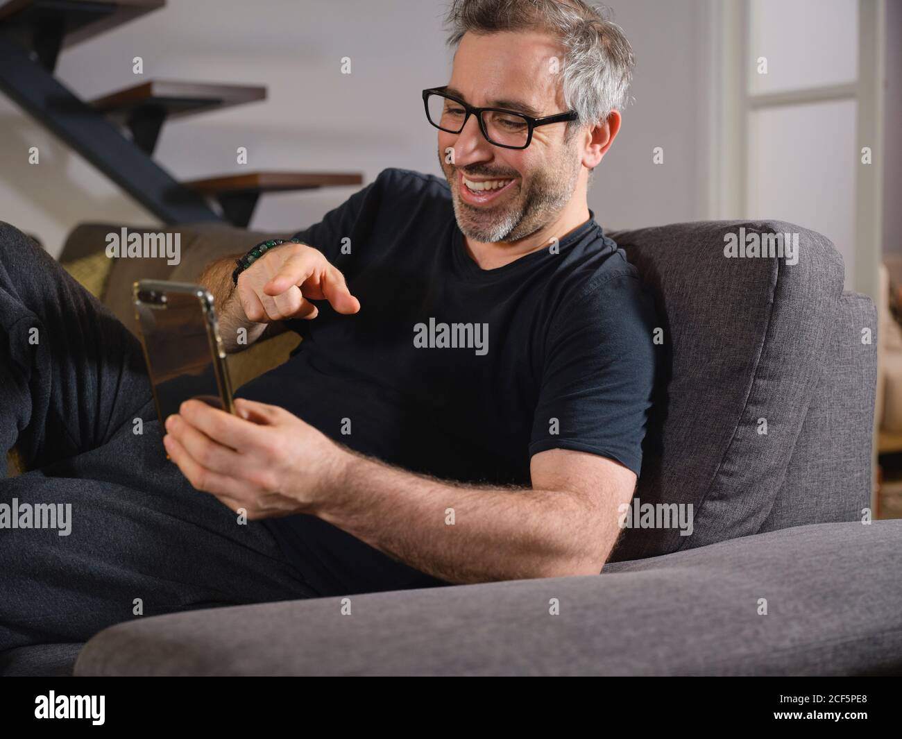 Relaxed man talking on a video conference with the phone smiling alone ...