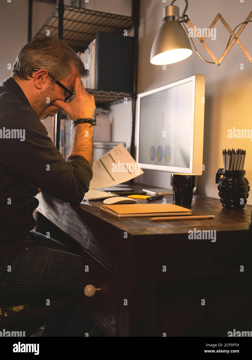 worried and overwhelmed man at home desk with computer with notes ...