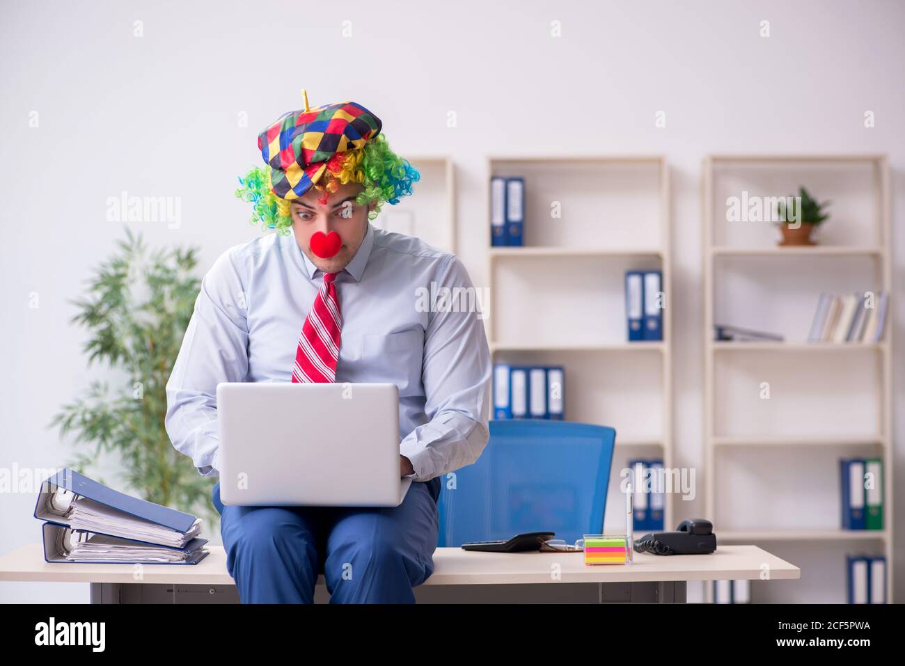 Funny employee clown working in the office room Stock Photo - Alamy