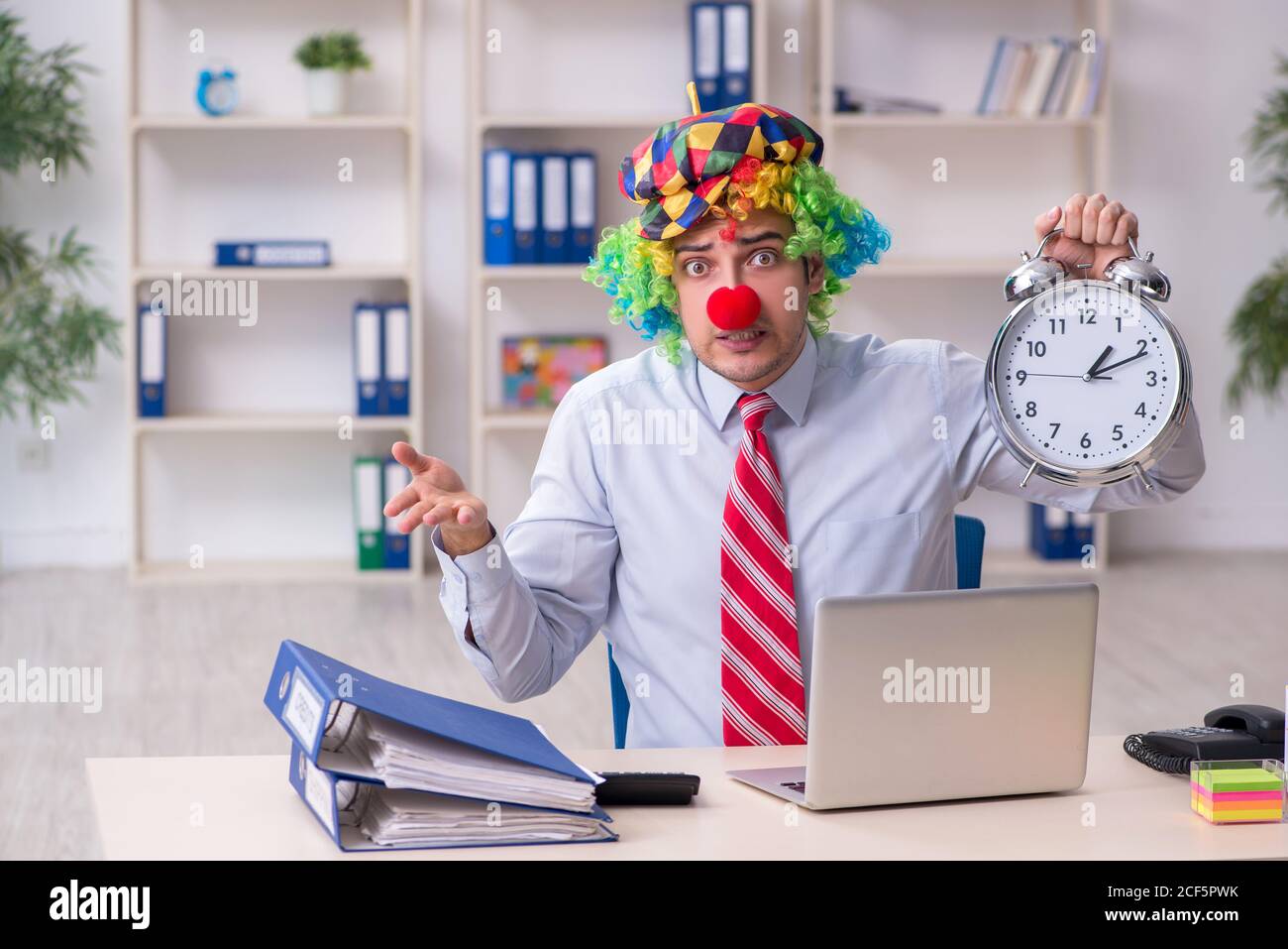 Funny employee clown working in the office room Stock Photo - Alamy