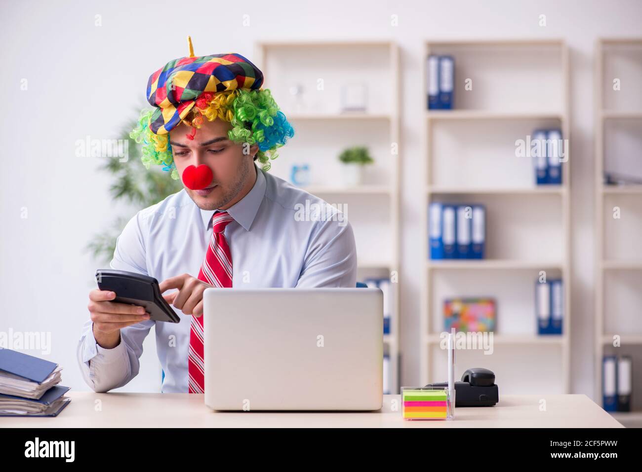 Funny employee clown working in the office room Stock Photo - Alamy