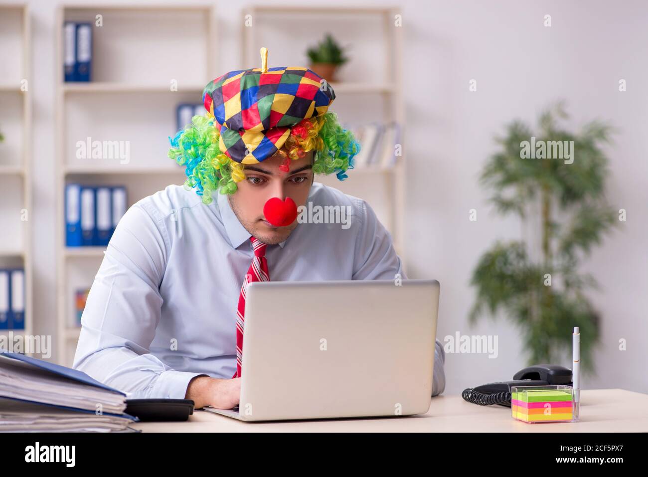 Funny employee clown working in the office room Stock Photo - Alamy