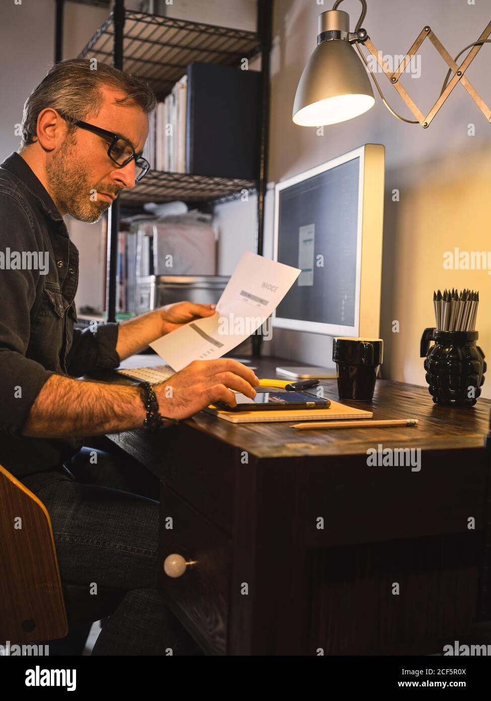 worried man doing calculations at home desk with computer with notes ...