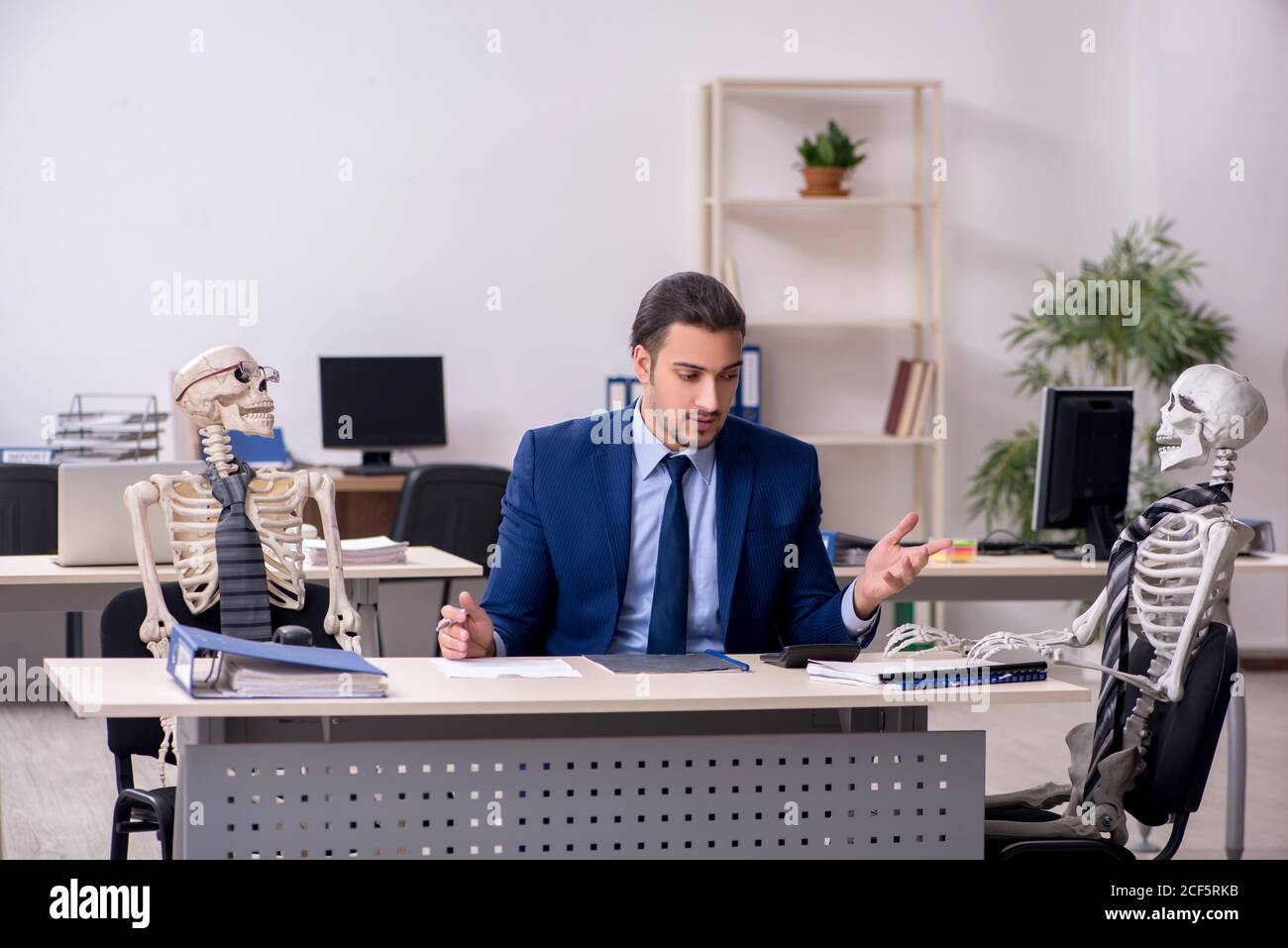 Young employee with skeletons in the office Stock Photo - Alamy