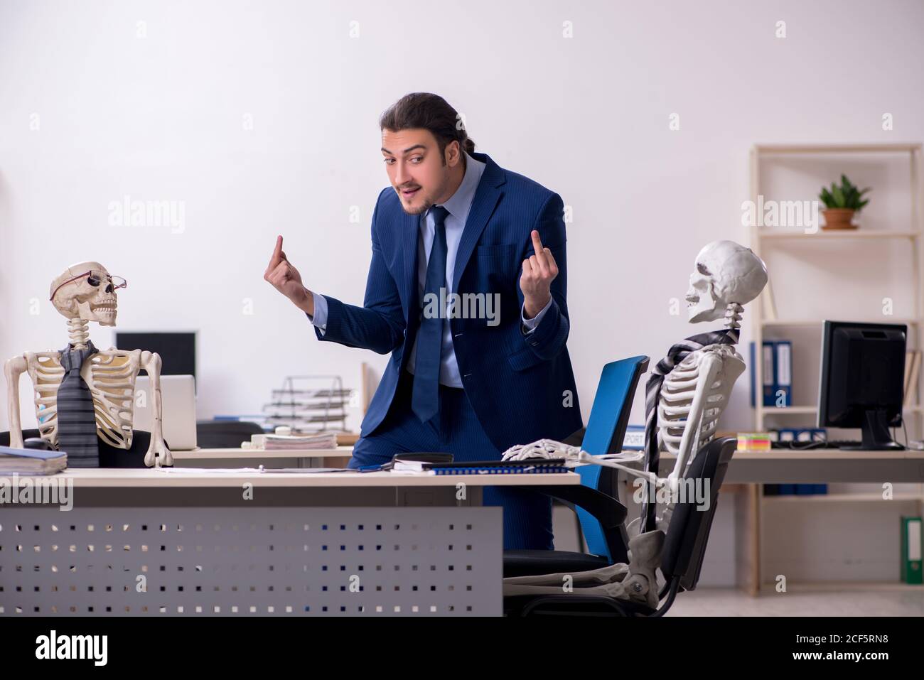 Young employee with skeletons in the office Stock Photo - Alamy