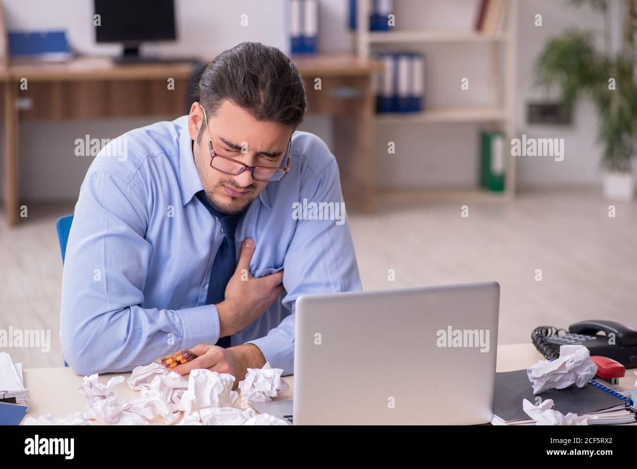 Sick male employee suffering at the workplace Stock Photo - Alamy