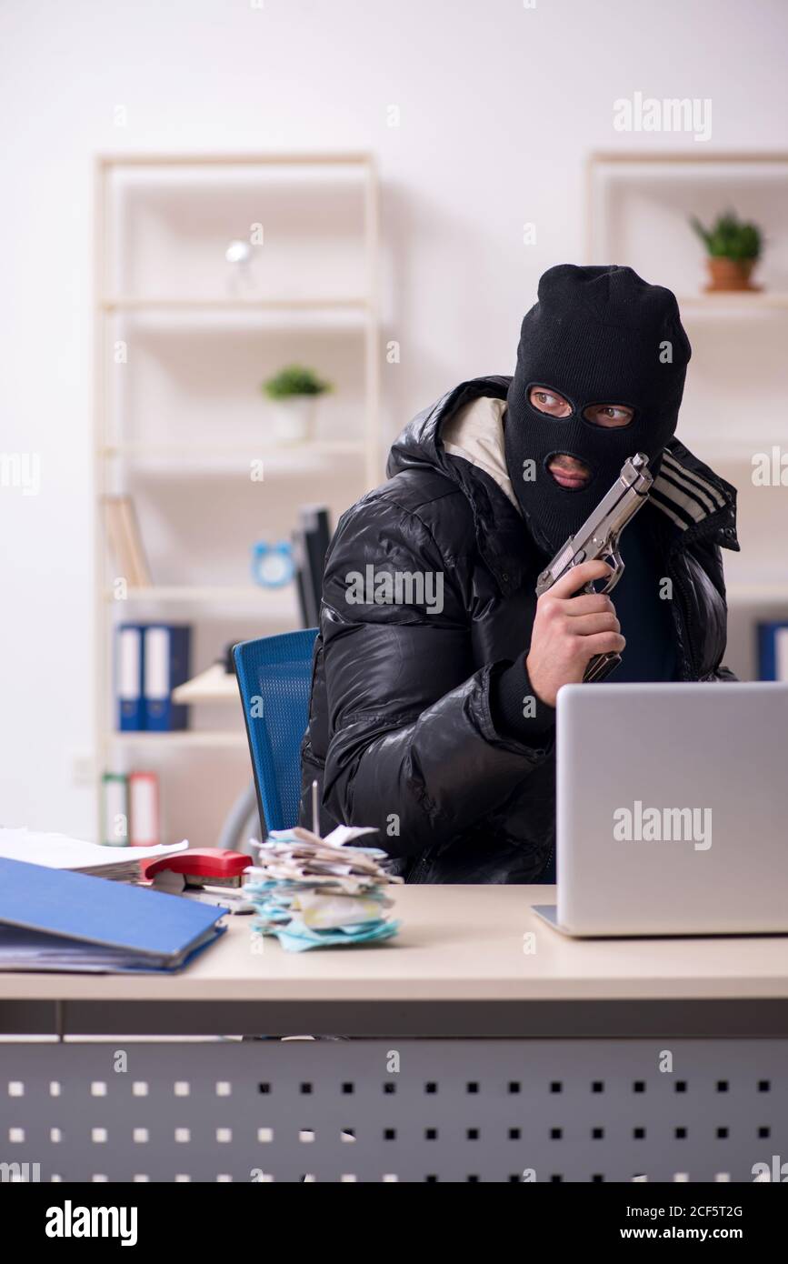Young male burglar in the office room Stock Photo - Alamy