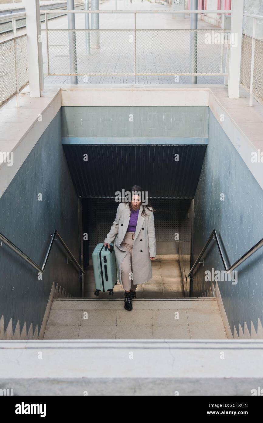 From above of elegant stylish young female traveler with suitcase ...