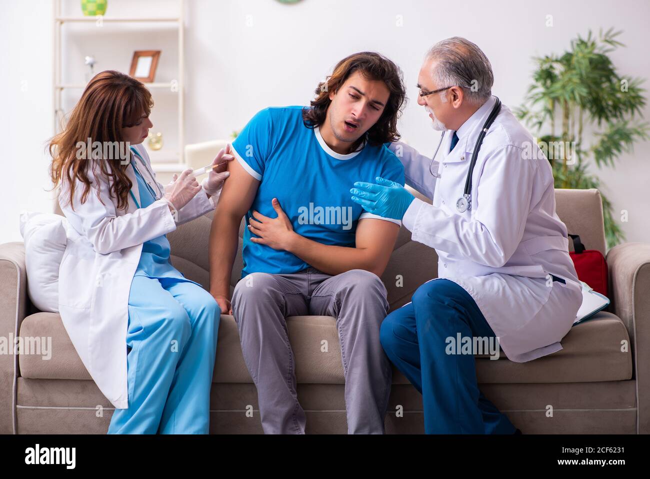 Two doctors visiting sick man at home Stock Photo - Alamy