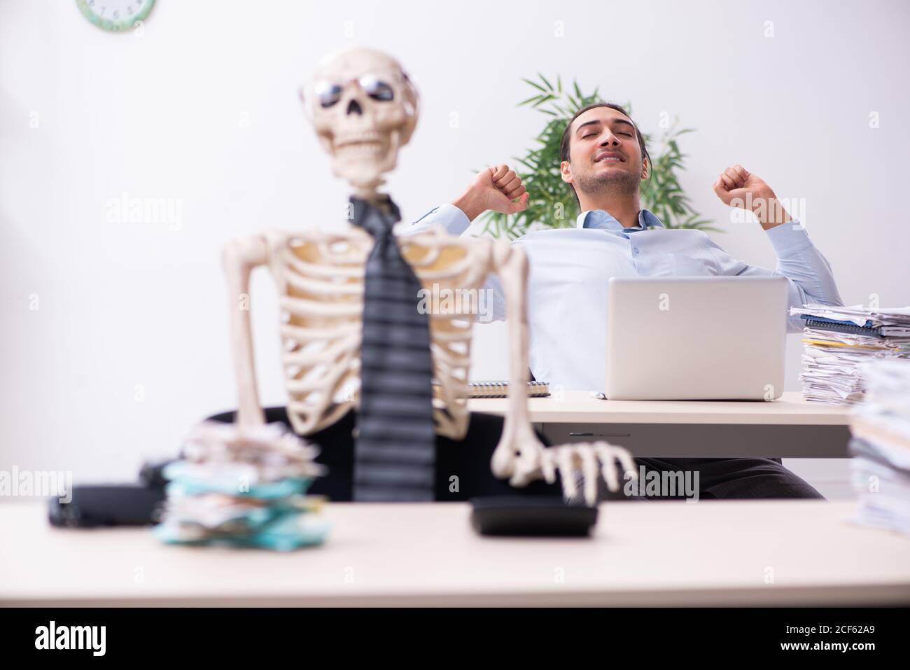 Young employee and skeleton in the office Stock Photo - Alamy