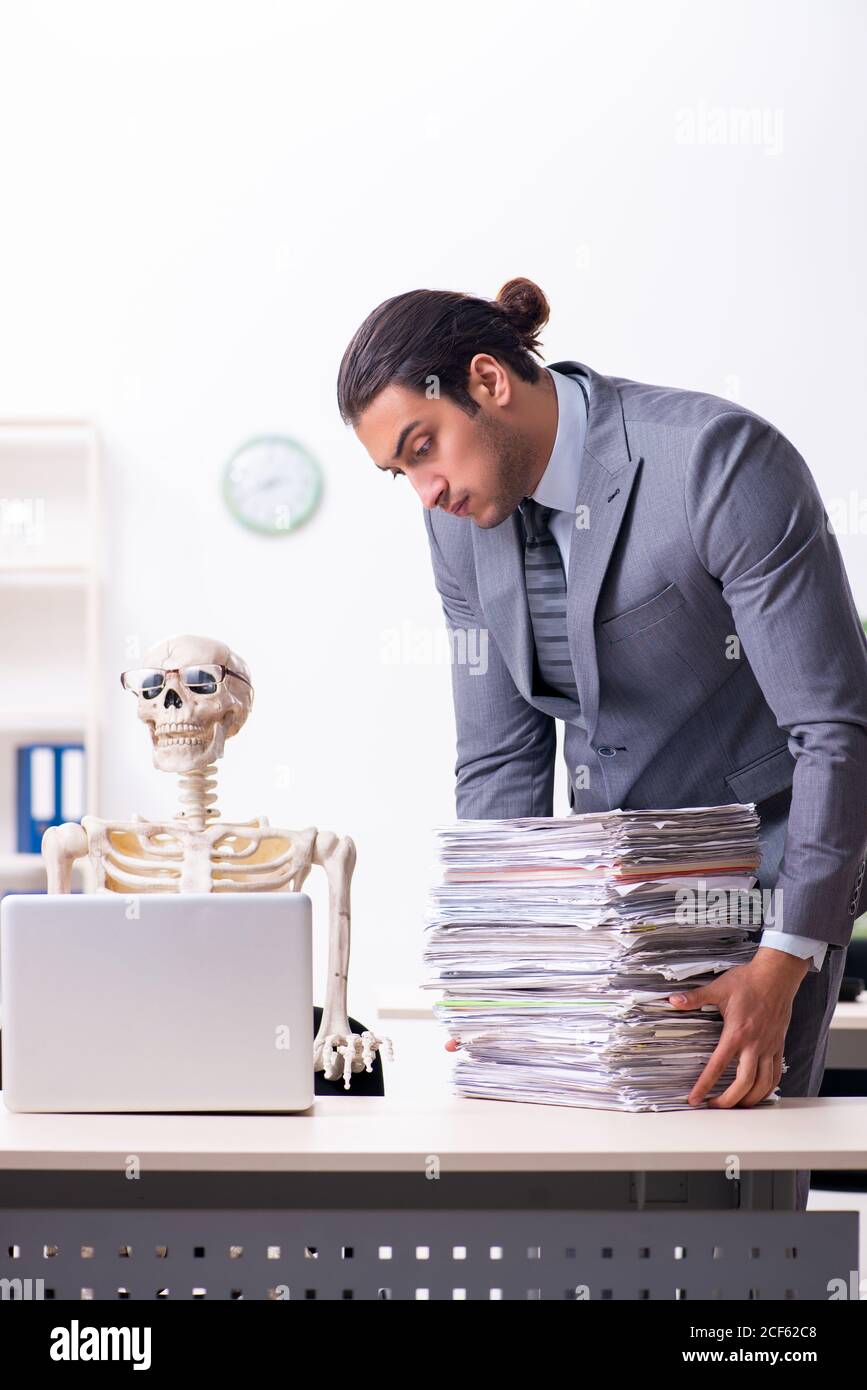 Young employee and skeleton in the office Stock Photo - Alamy