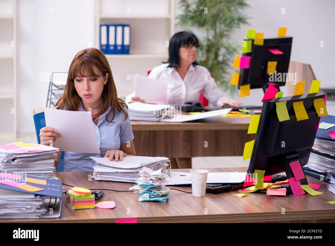 Two employees and excessive work in the office Stock Photo - Alamy