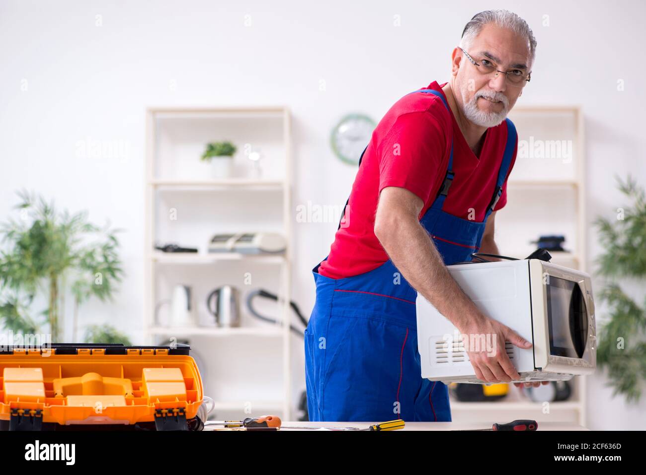 Old repairman repairing appliances in his workshop Stock Photo - Alamy
