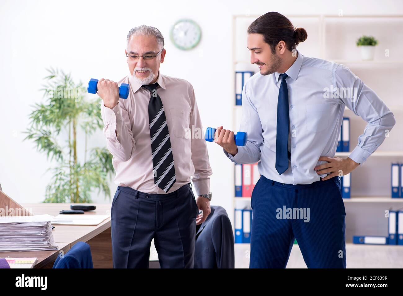 Two employees doing physical exercises at the workplace Stock Photo - Alamy