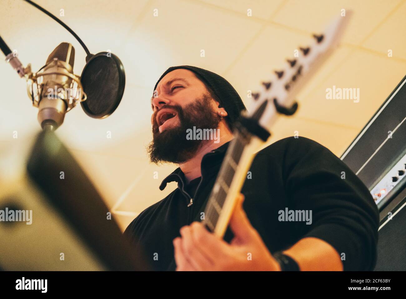 Man playing a guitar and singing into a microphone hi-res stock ...