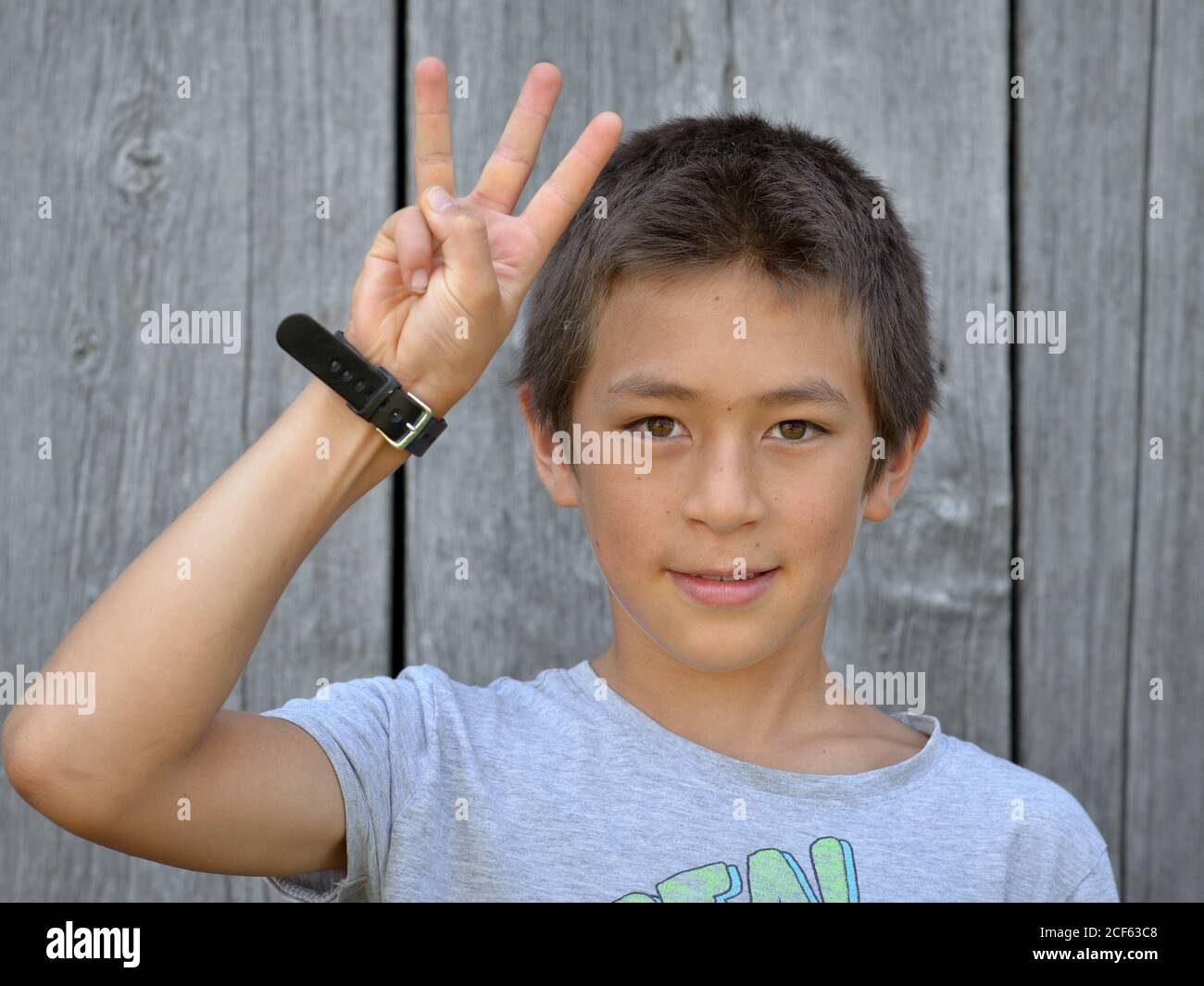 Mixed-race pre-teen boy (East Asian and Caucasian) shows with his right ...