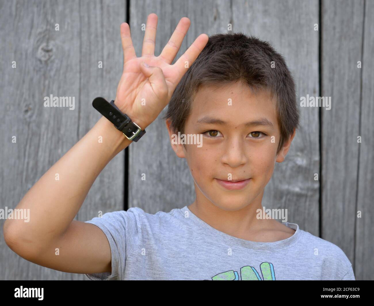 Mixed-race pre-teen boy (East Asian and Caucasian) shows with his right ...