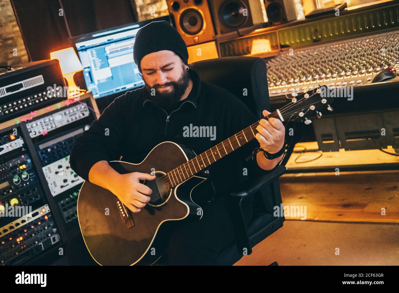 Adult man sitting in music studio playing a guitar Stock Photo - Alamy