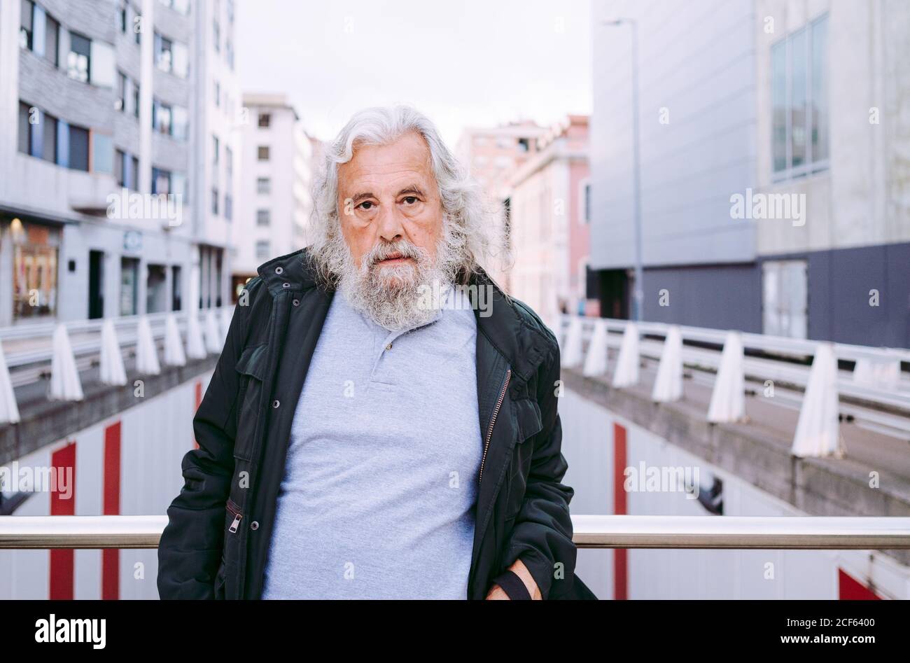 Serious bearded man with gray hairs wearing casual outfit and looking ...