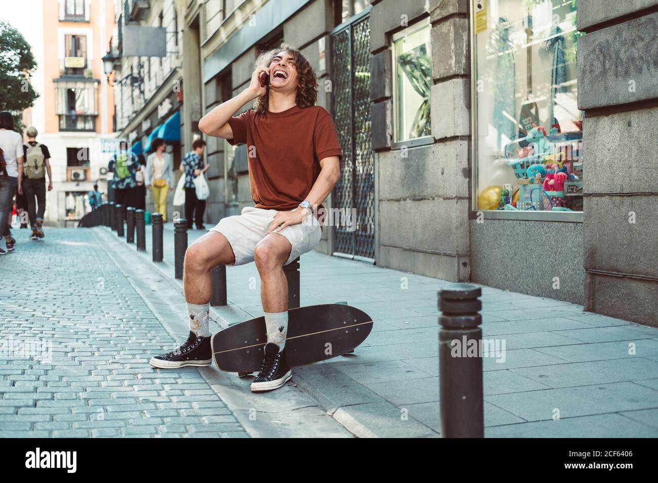 Cheerful casual man laughing and speaking on smartphone while sitting ...