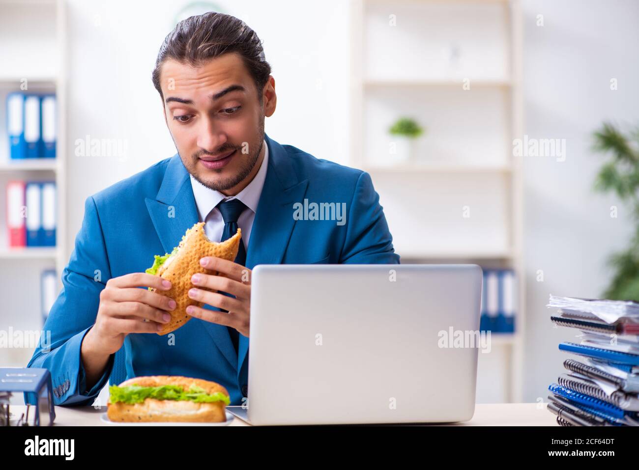Young employee having breakfast at workplace Stock Photo - Alamy