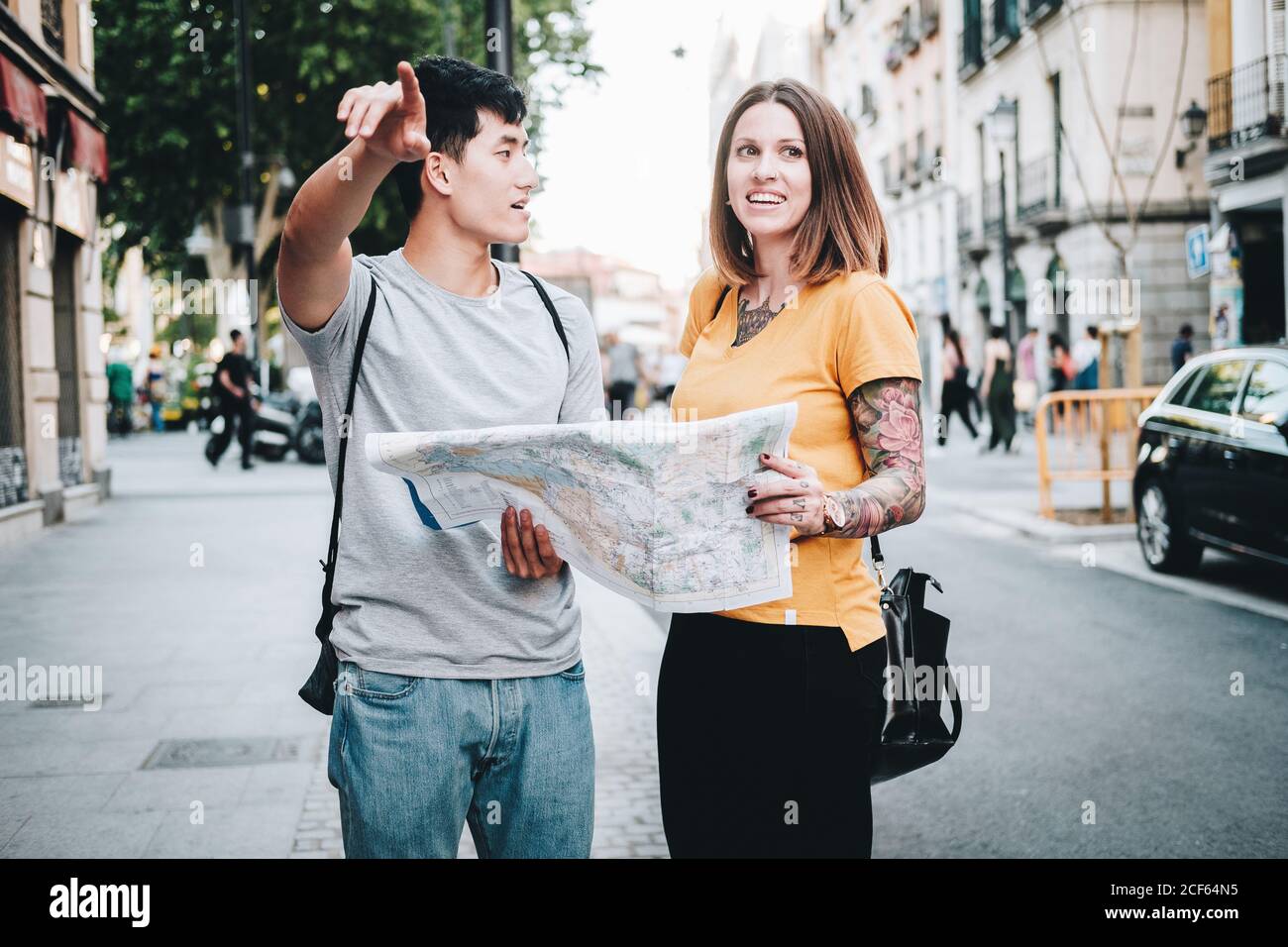Positive laughing multiethnic people looking for direction on map while ...
