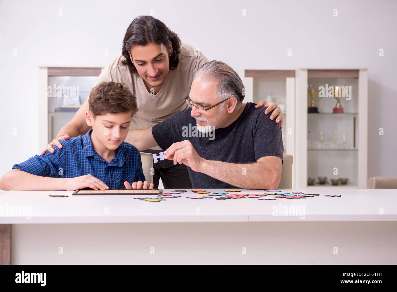 Three generations of family playing jigsaw puzzle Stock Photo - Alamy