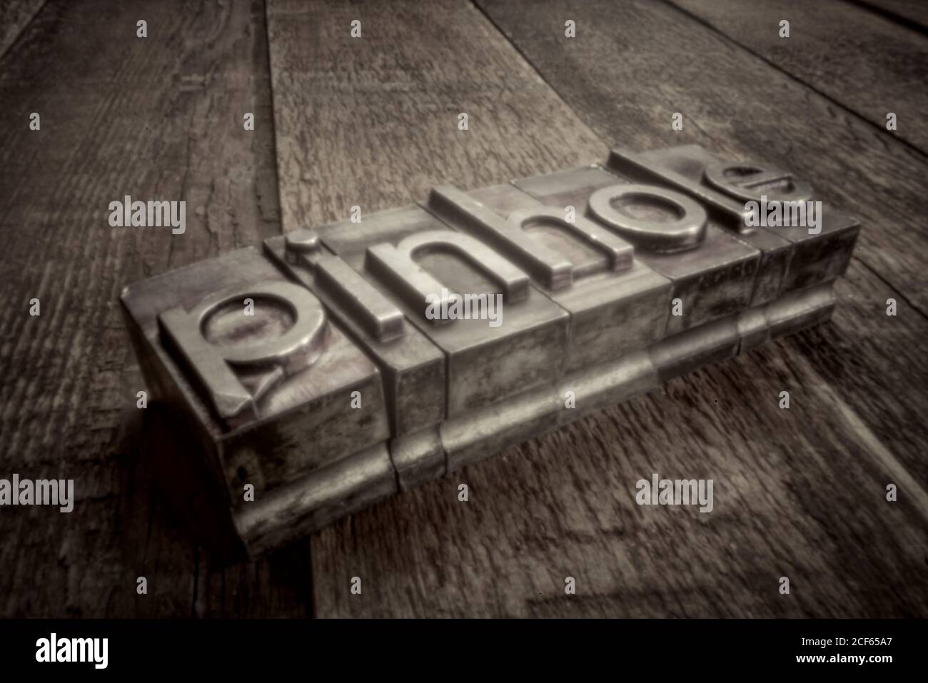 pinhole word in gritty letterpress metal type over weathered wood, soft ...