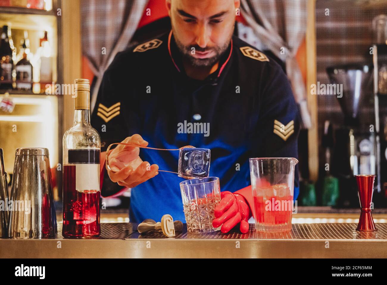 From above large rectangular ice cube in hand of barman in uniform and ...
