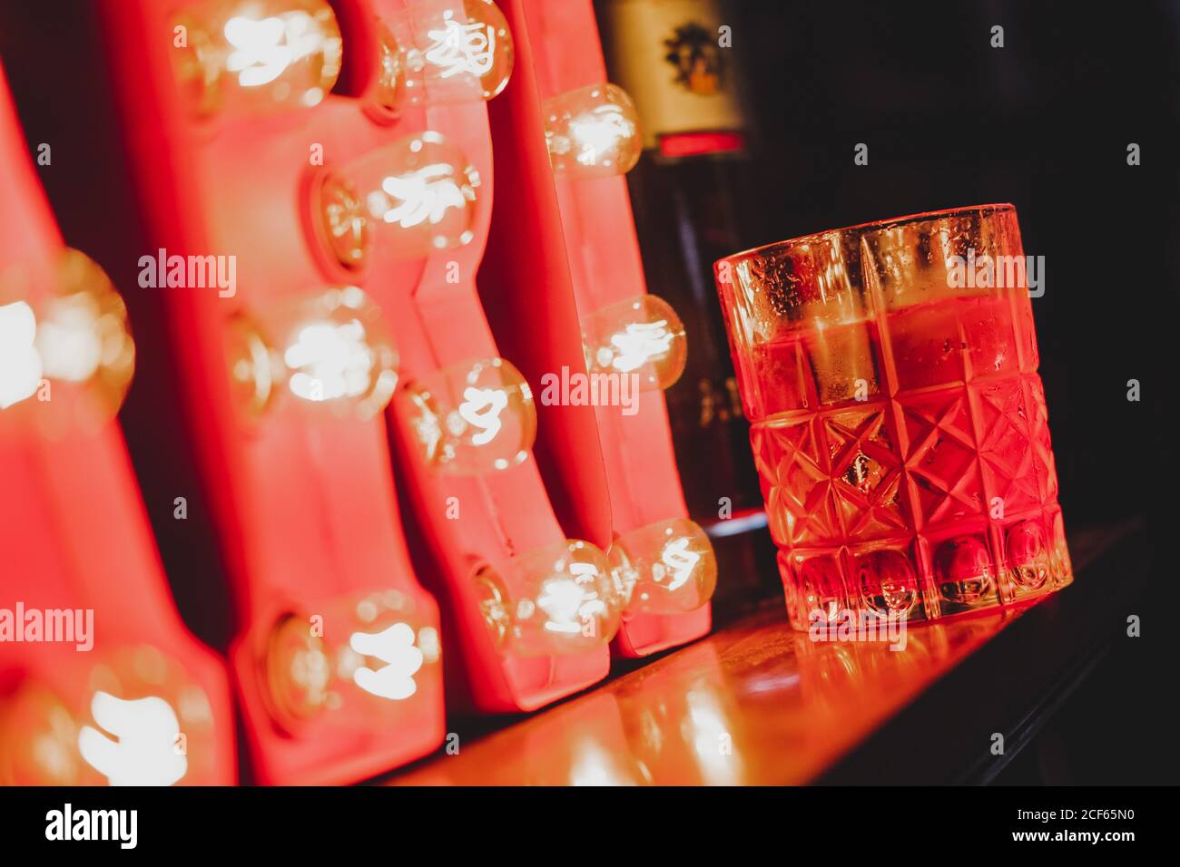 Red cocktail in bowl and bright red element with burning lights on bar ...