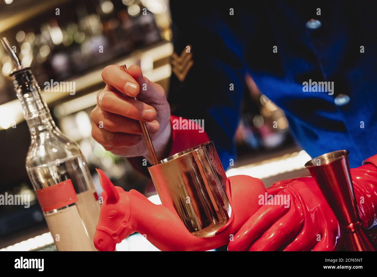 unrecognizable barman in uniform and red gloves preparing cocktail for ...