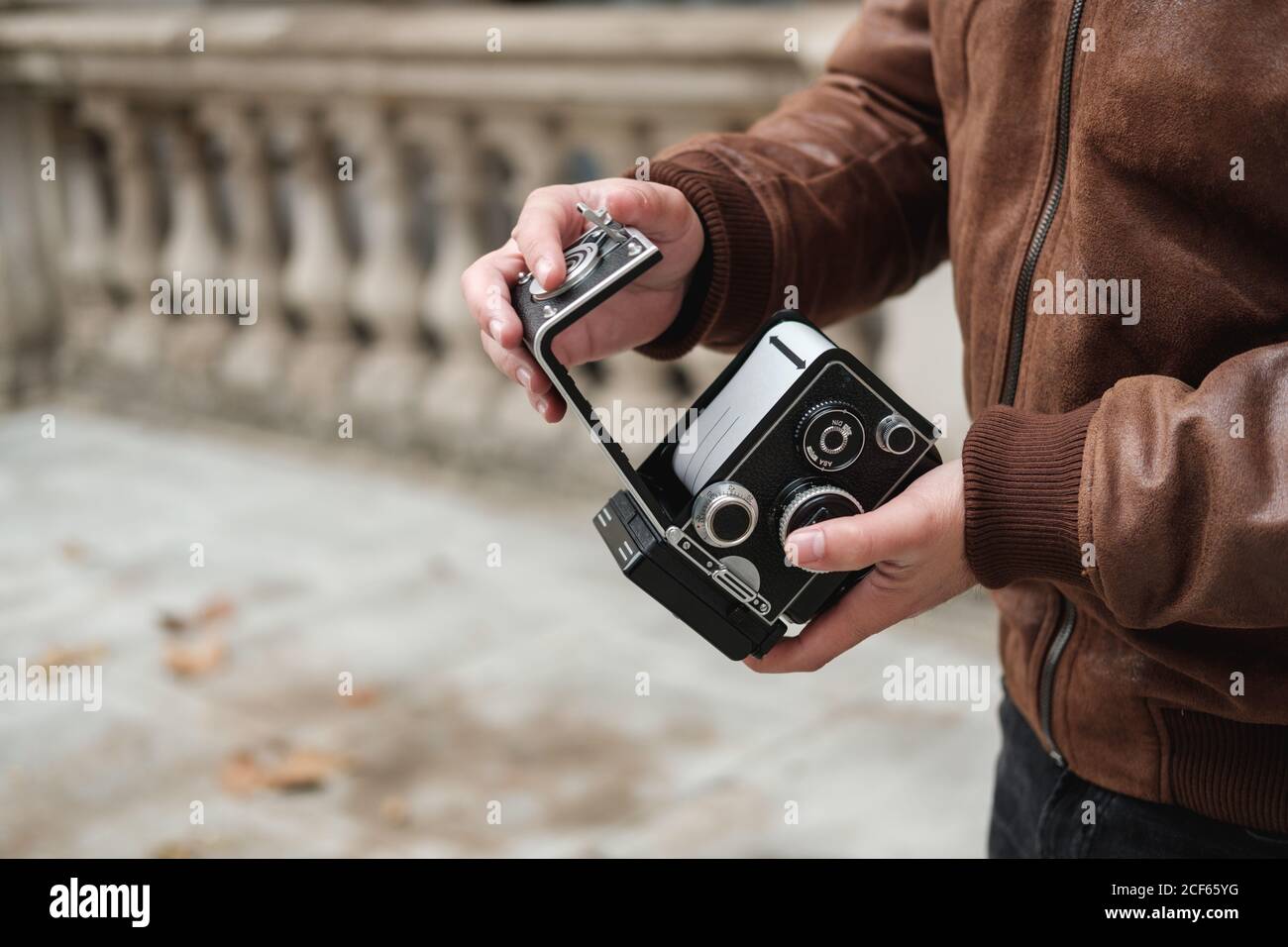 unrecognizable tourist changing film in retro photo camera while ...