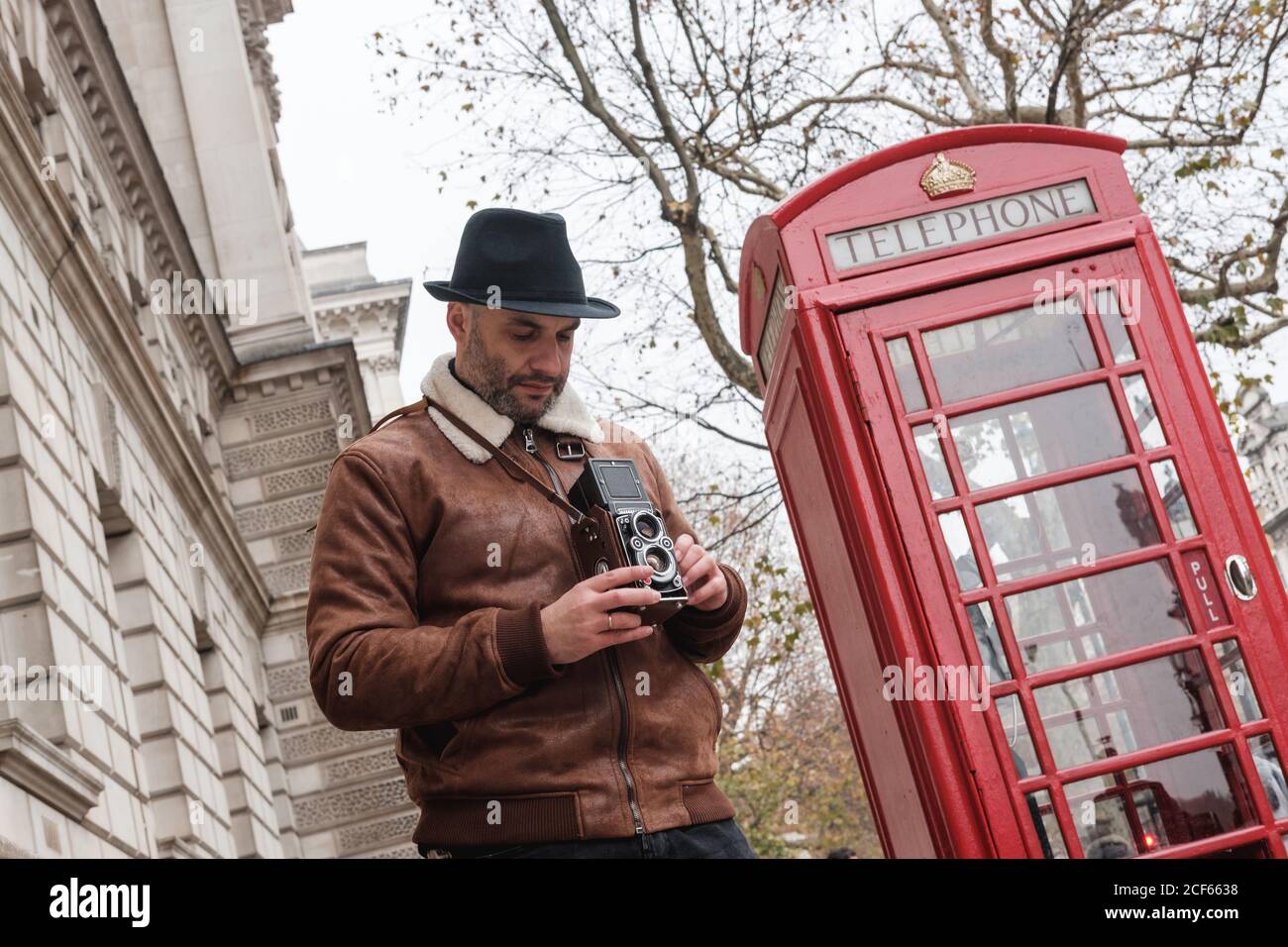 From below man with retro photo camera while standing on London street ...
