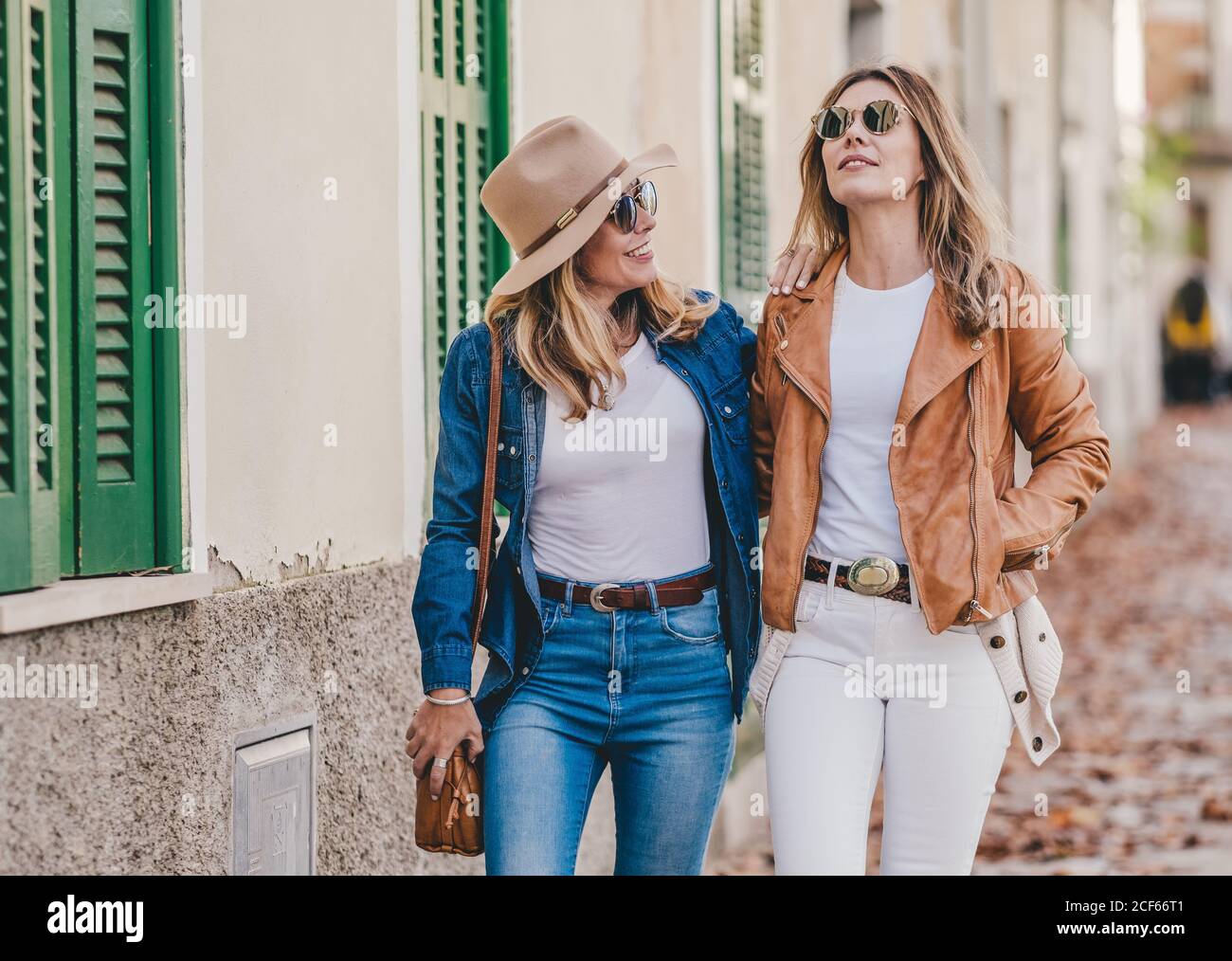 Stylish relaxed Woman chatting to each other happily while walking down ...