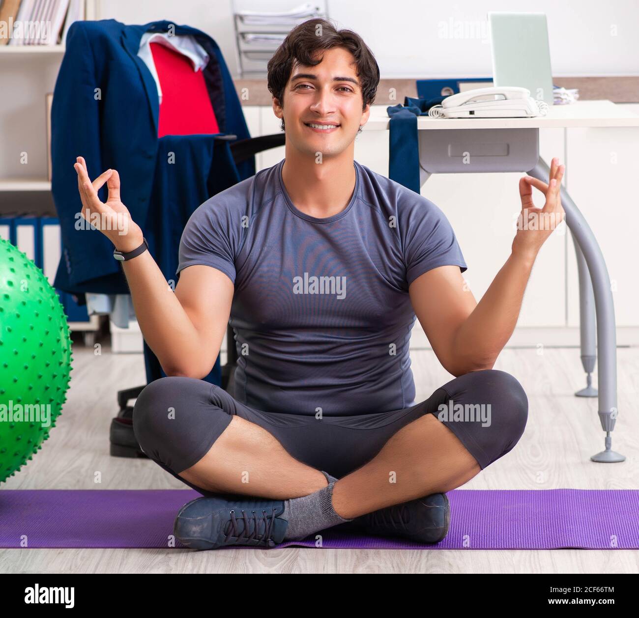 The young male employee exercising in the office Stock Photo - Alamy