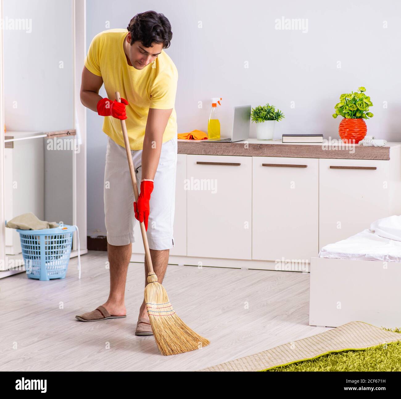 The young handsome man cleaning in the bedroom Stock Photo - Alamy