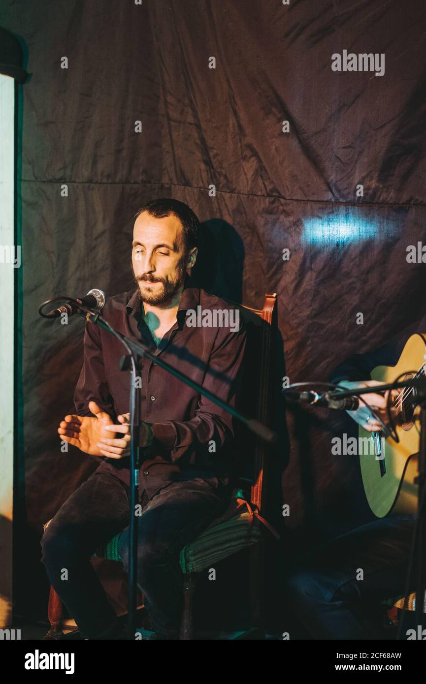 Hispanic male singer in black wear singing into microphone while ...