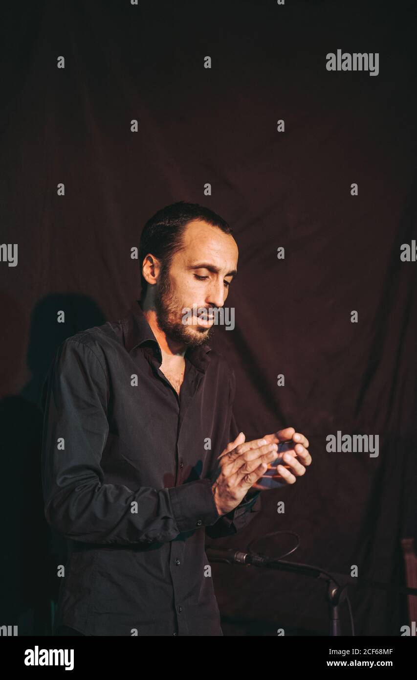 Adult Hispanic musician clapping while singing flamenco song on stage ...