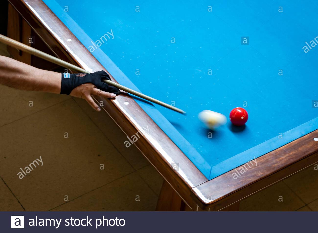 Player's arm holding cue above pool table. The player has just struck ...