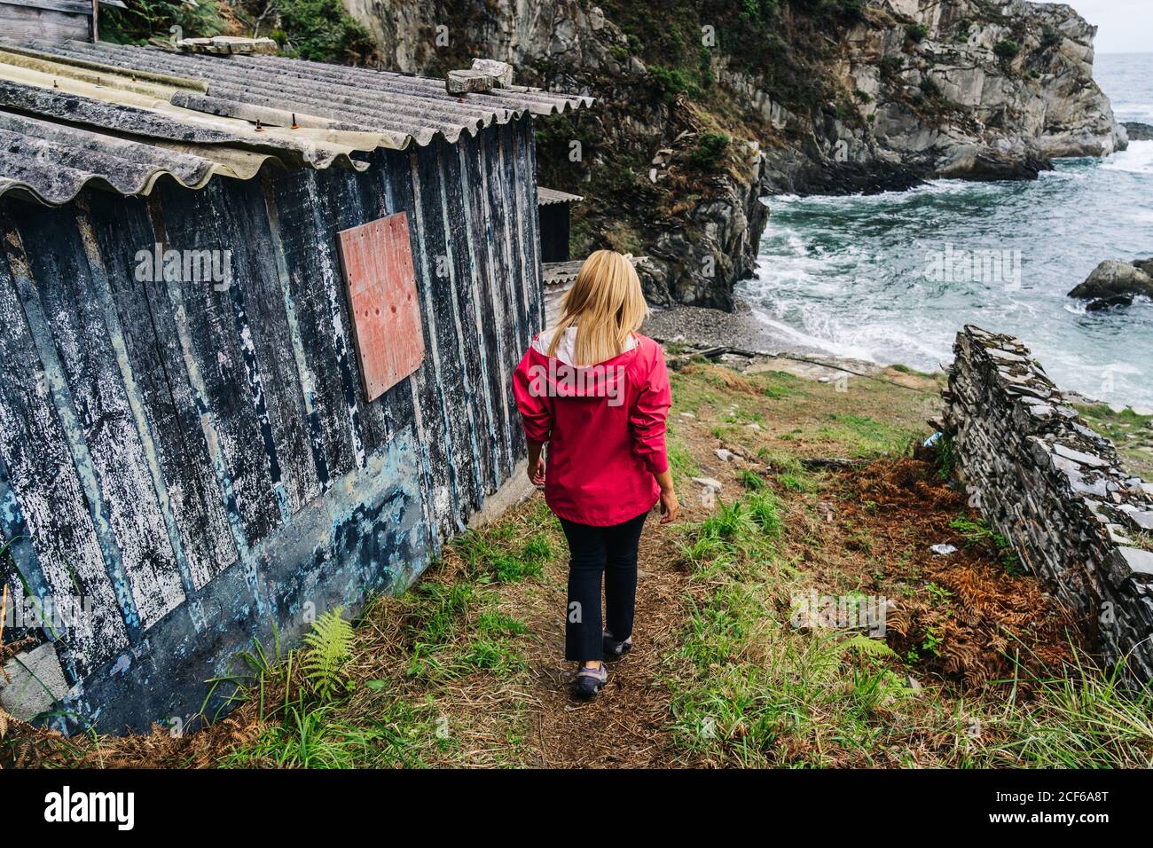 Woman walking down on stone steps leading down to foamy sea Stock Photo ...