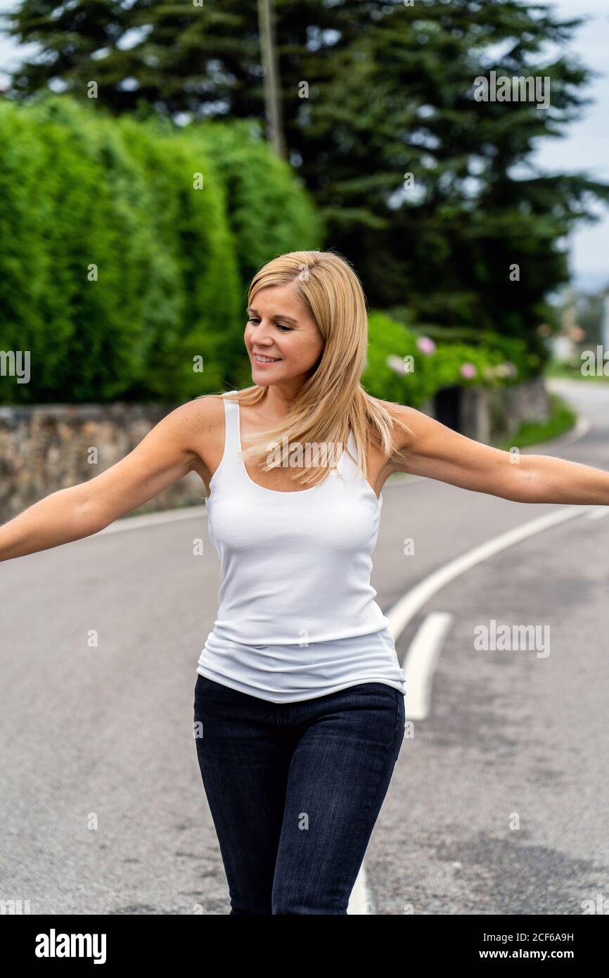 Joyful Woman walking on marked road looking away Stock Photo - Alamy