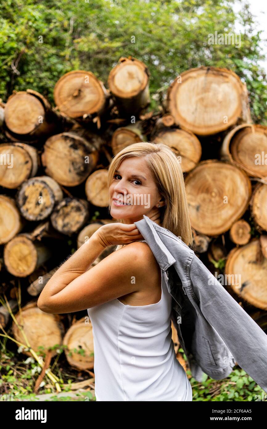 Woman taking off jacket on background of woodpile in forest Stock Photo ...